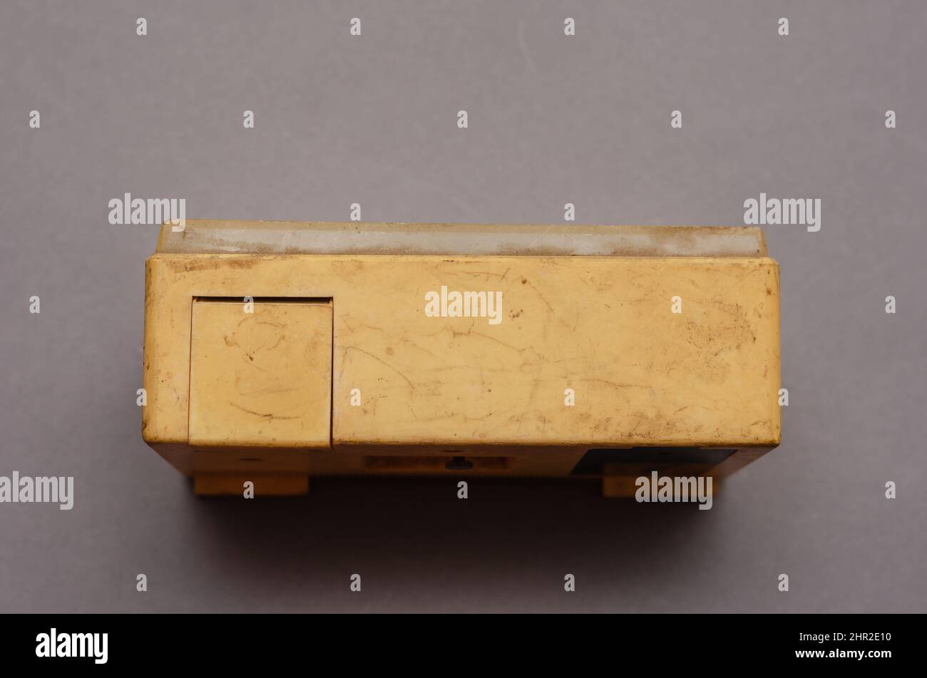 Top side of old yellow alarm clock against gray background. Rectangular ...