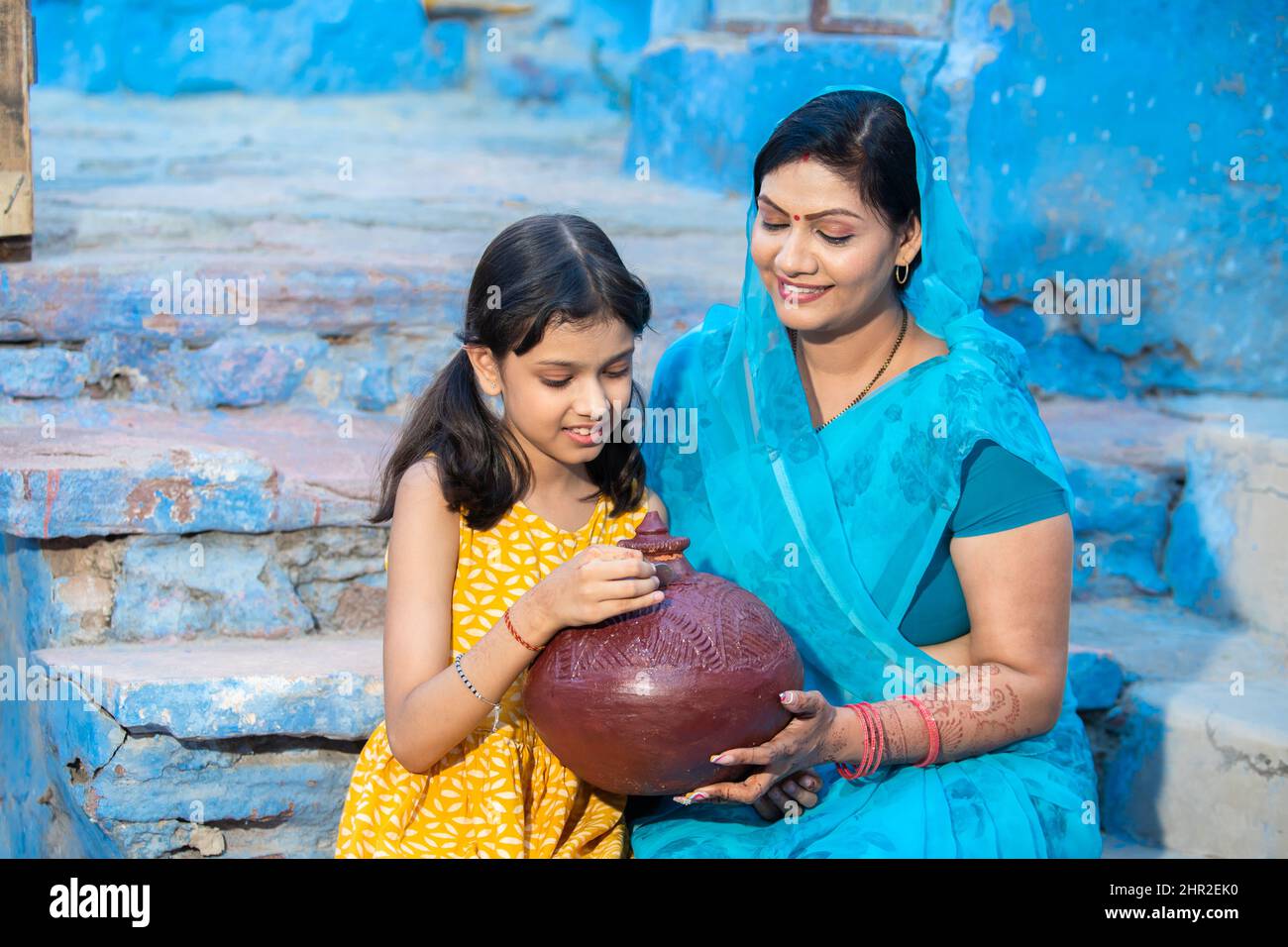 Happy Indian daughter put coin clay money box or gullak while her ...