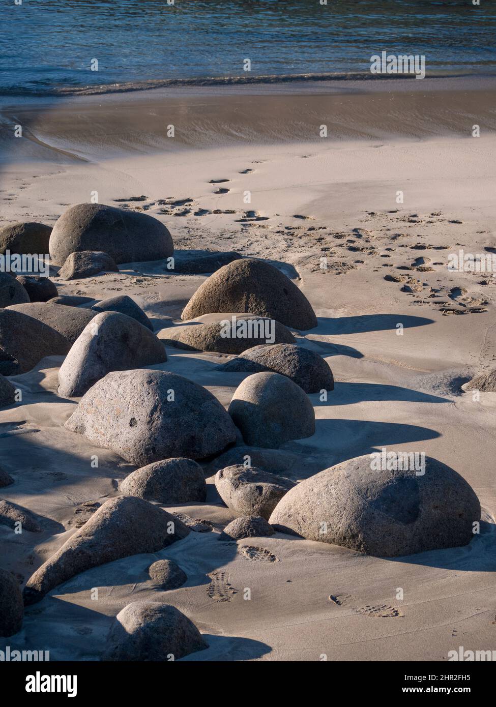 Boulder in the beach with human foot prints going to the water Stock ...