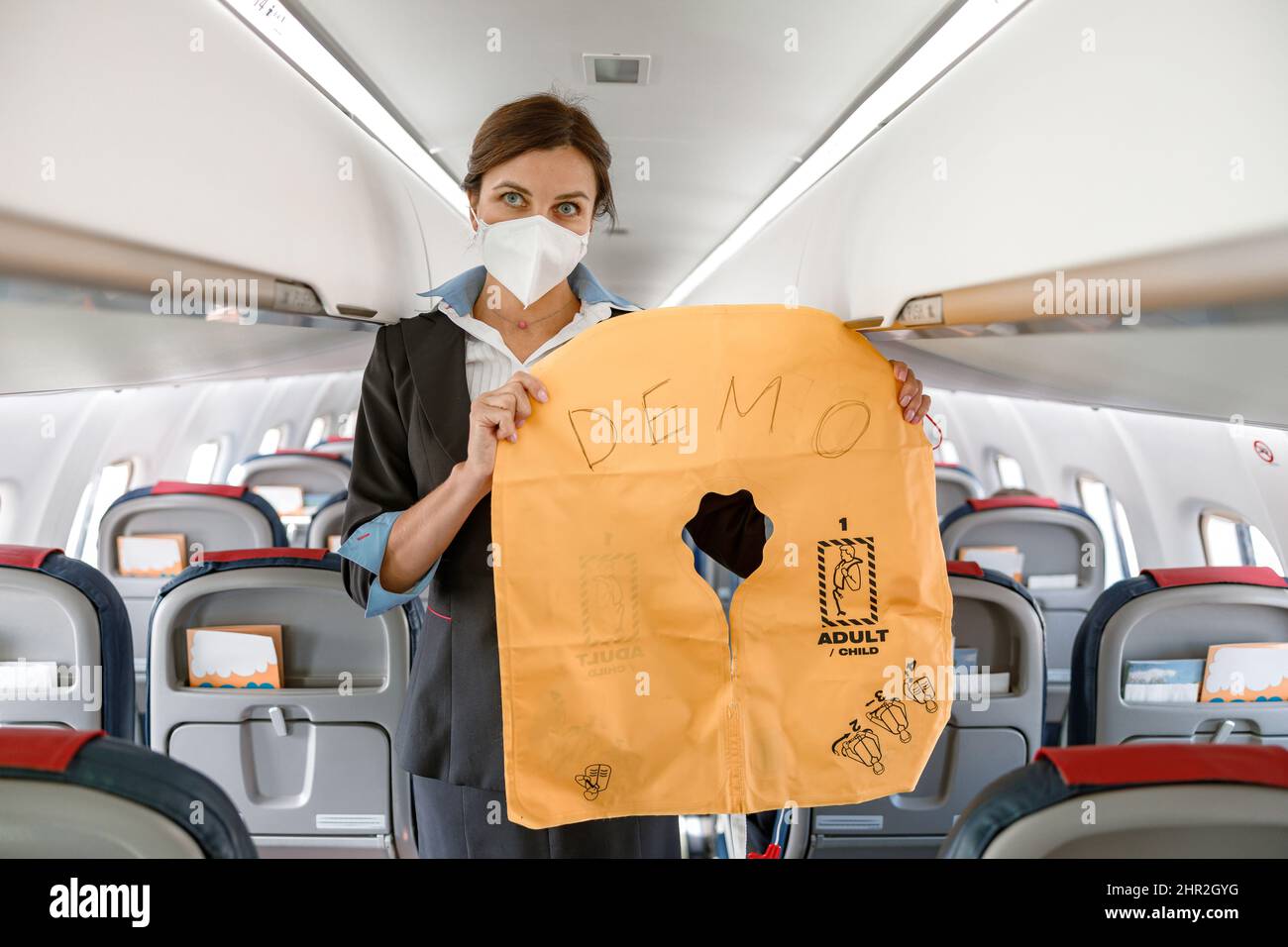 Female flight attendant in medial mask holding life vest Stock Photo ...