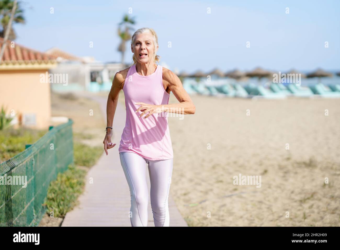 Older female doing sport to keep fit. Mature woman running along the shore of the beach Stock ...