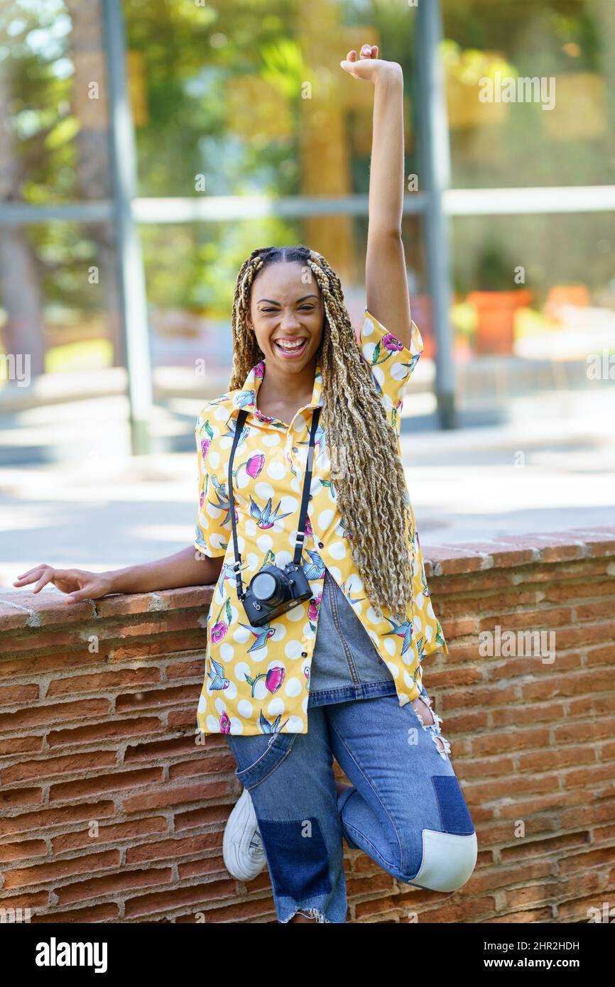 Black woman with African braids, raising her arm in joy. Girl holding a ...