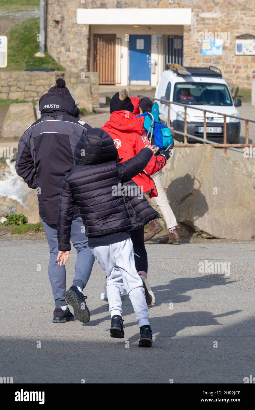 A young boy struggling to stand as he walks behind his parents in ...