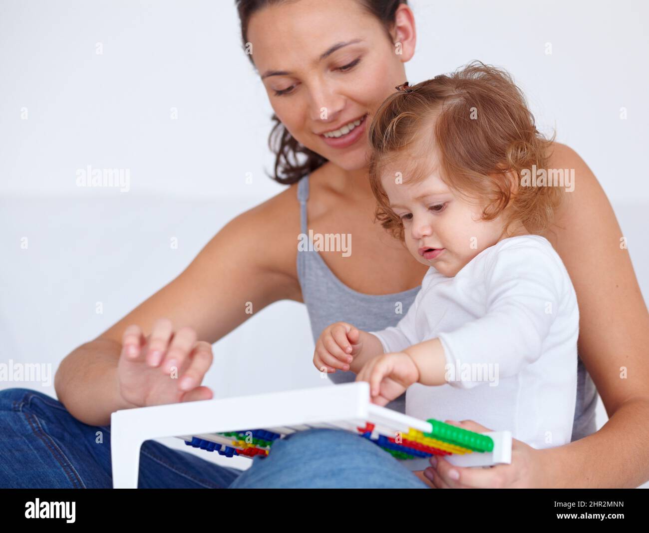 Learning is fun. A cute baby girl being taught by her mother how to use ...