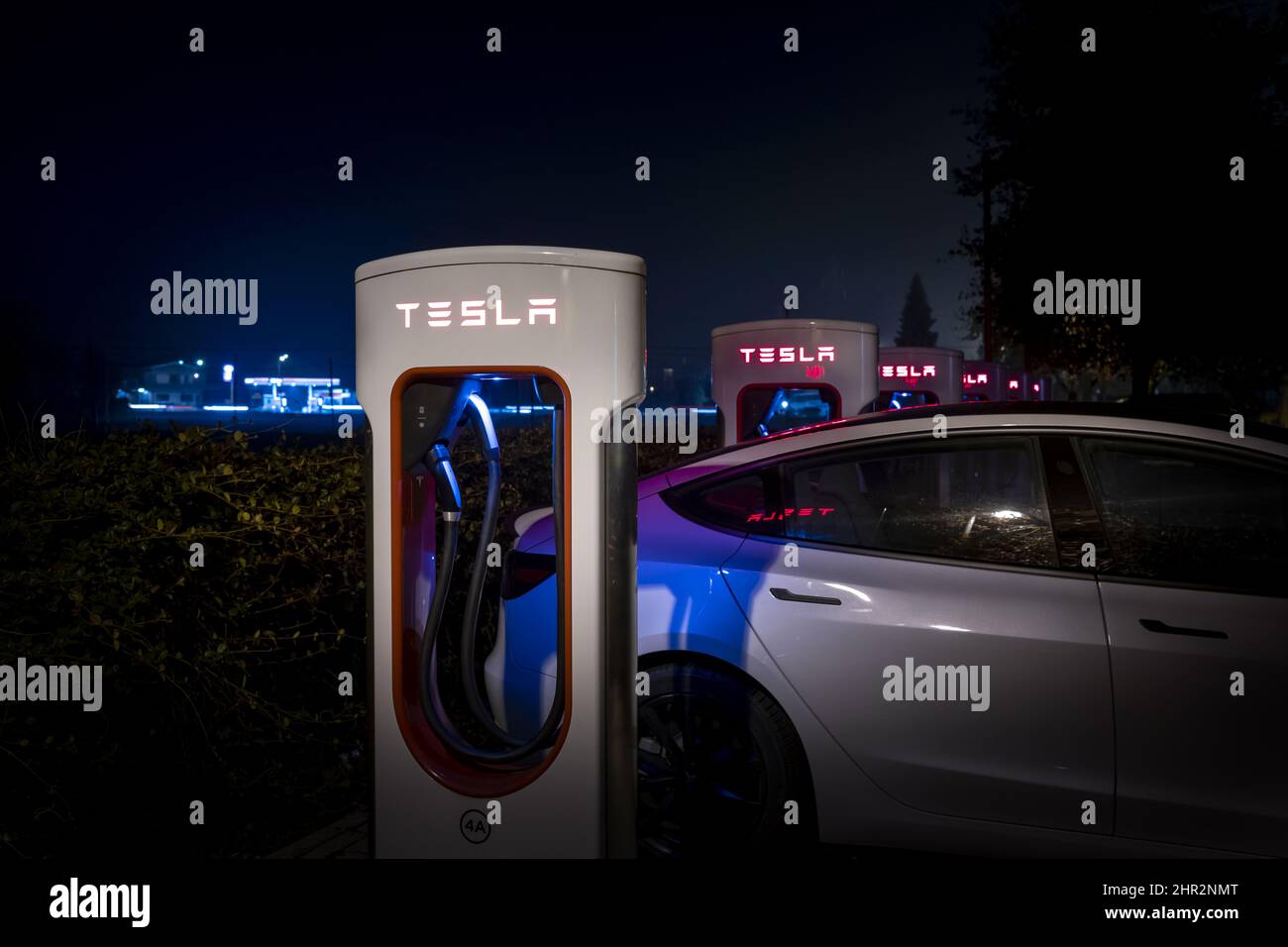 Tesla supercharger station at night with a parked white car Stock Photo ...
