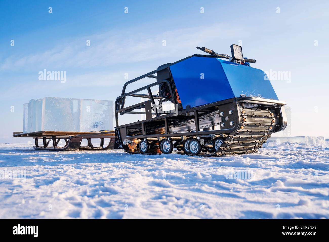 Tractor with a trailer carries blocks of ice on the ice of Lake Baikal ...