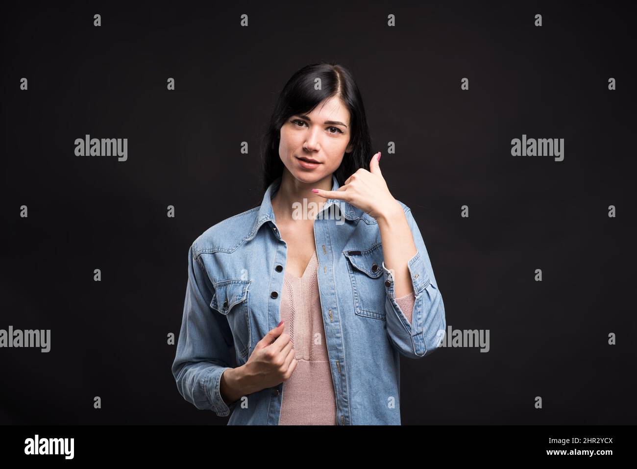 Attractive caucasian brunette girl in shirt showing phone call gesture ...