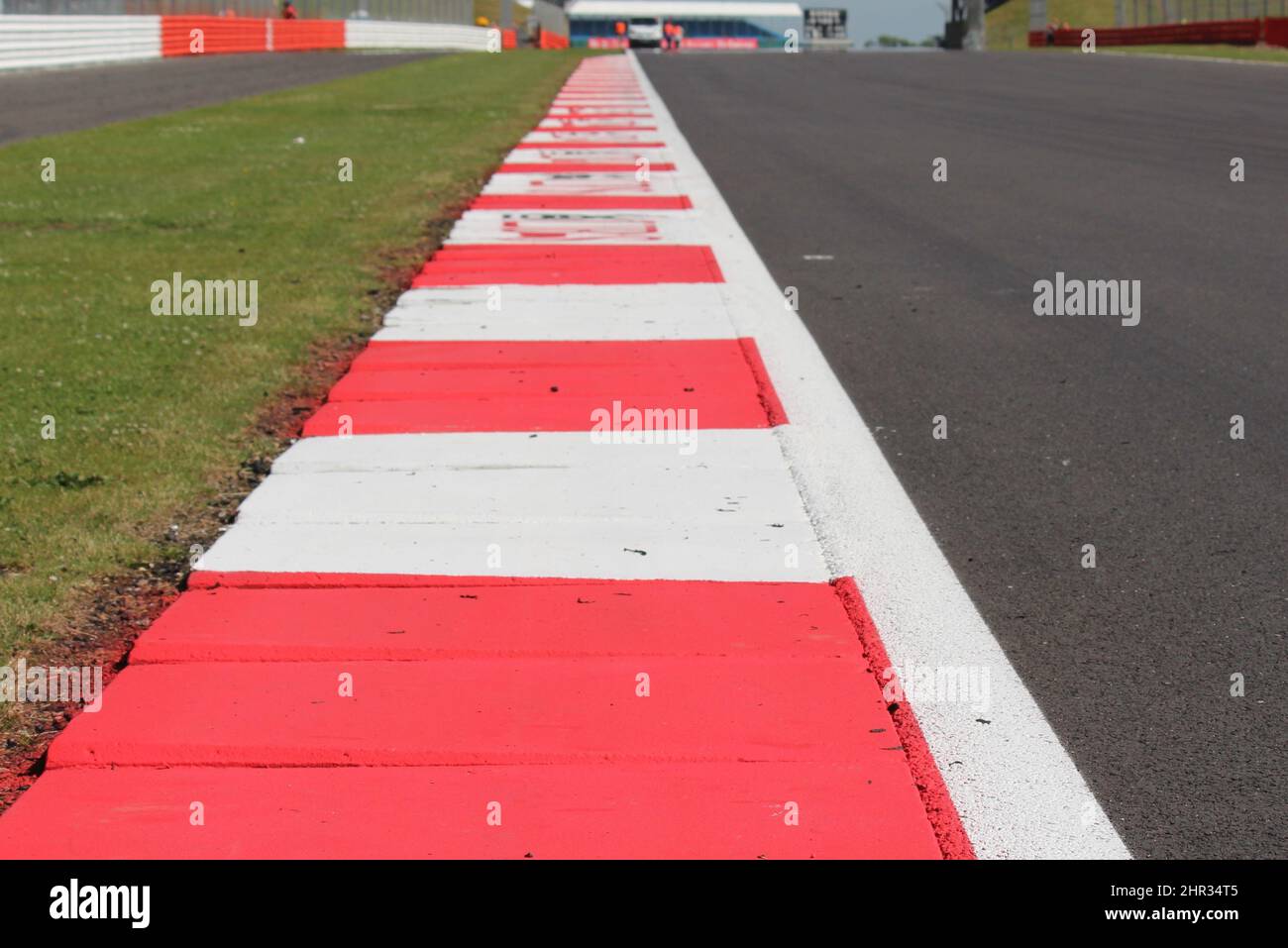 red and white curb on the edge of a long straight down a racing track ...
