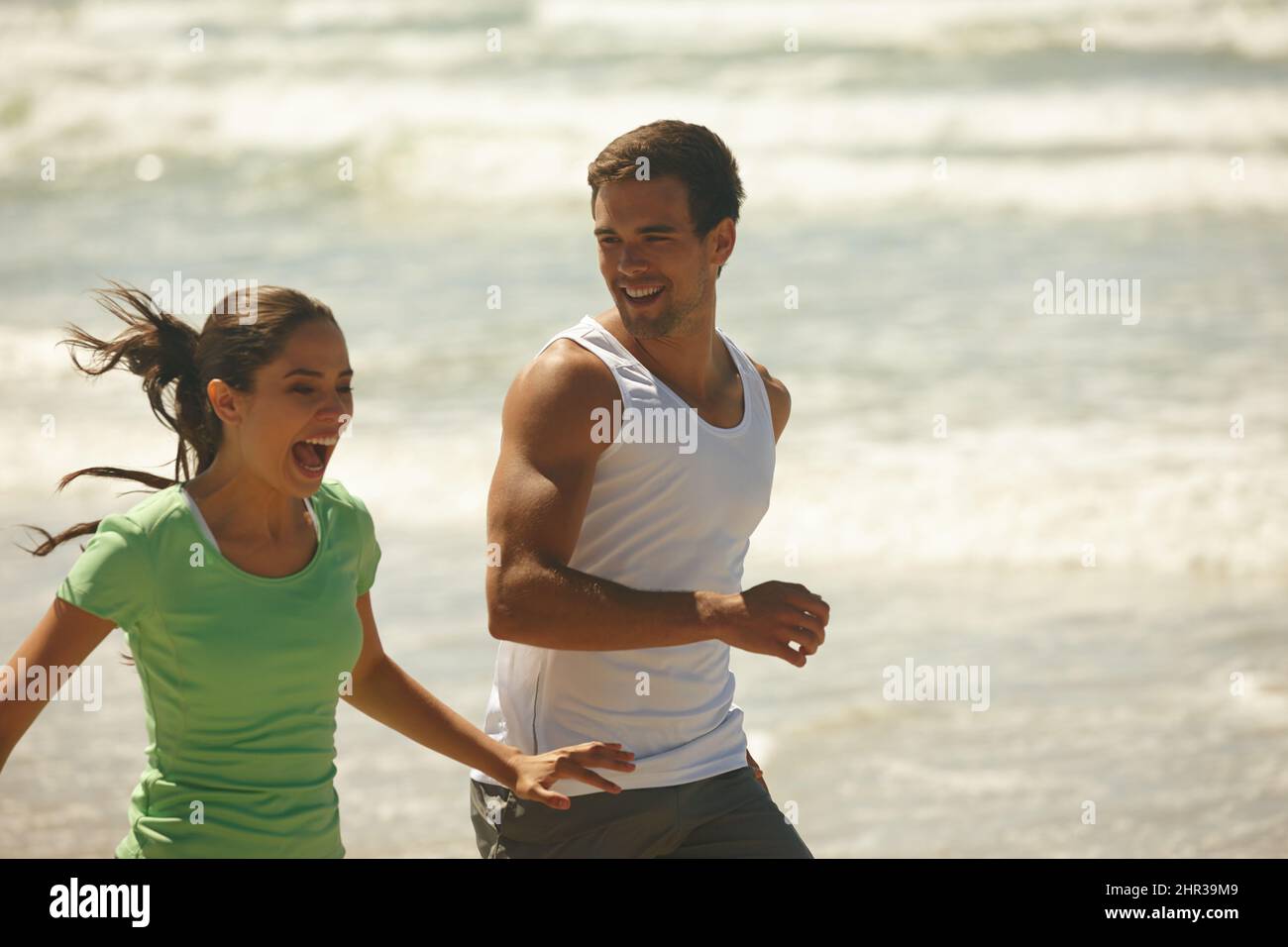 Catch me if you can. Shot of a laughing young couple jogging together ...