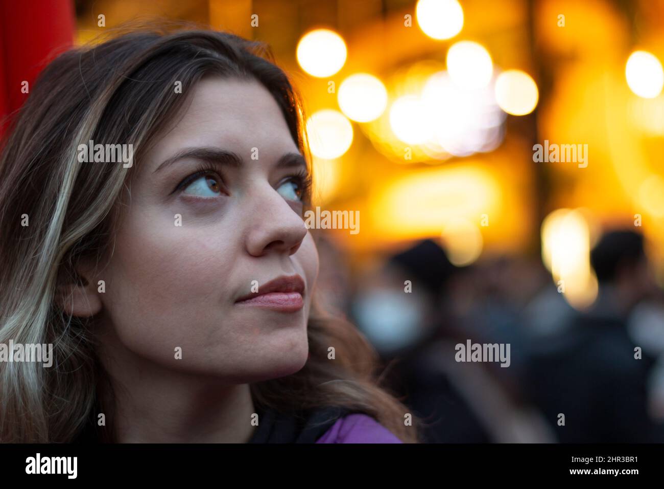A girl looking up while a singer sing behind her. Blonde girl in front ...