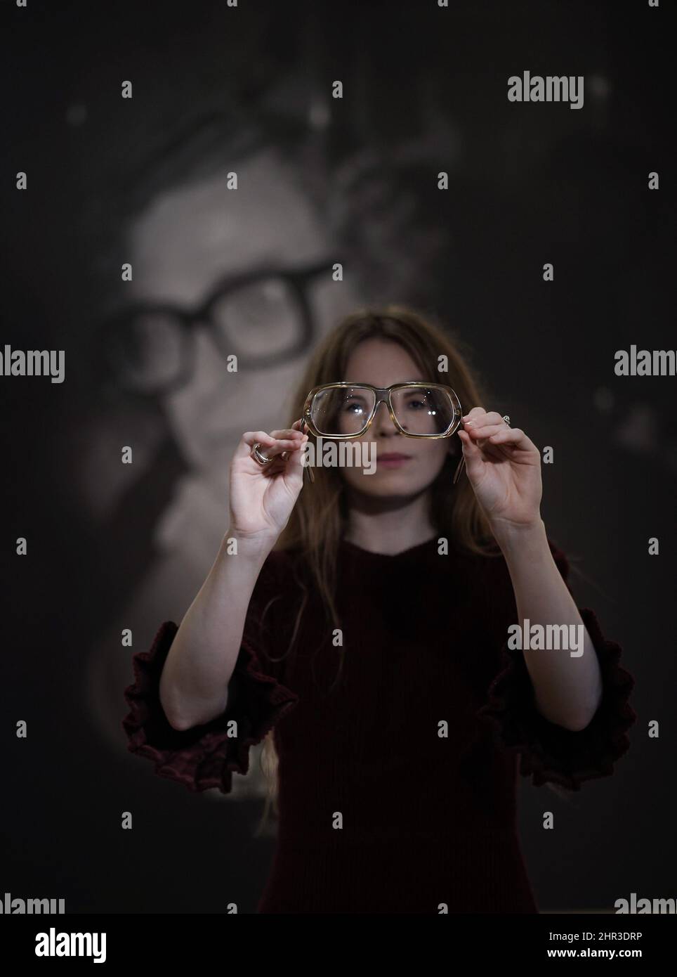 A member of staff holding a pair of spectacles belonging to Sir Michael ...