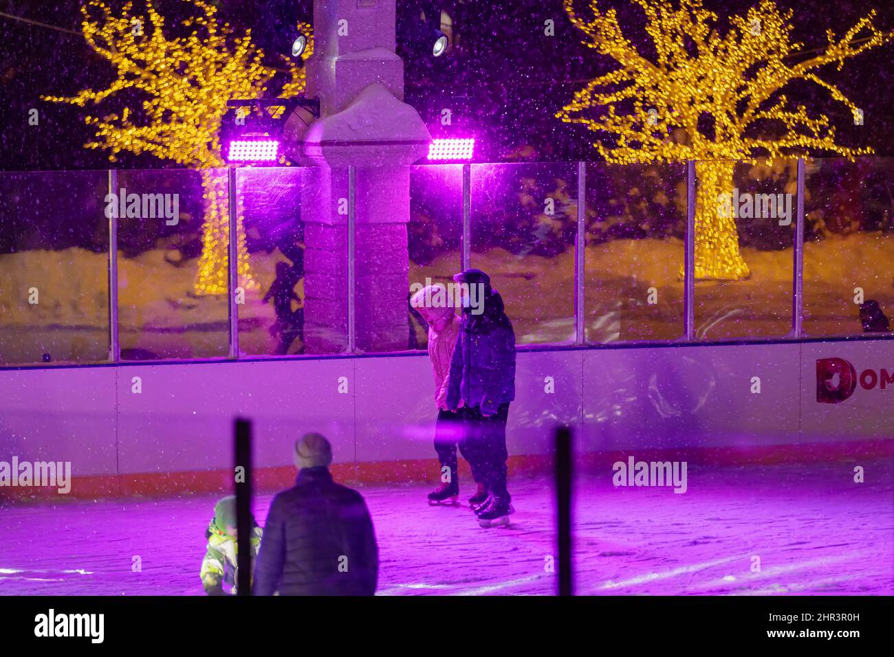People skate in the evening on a lighted ice rink. A blizzard is raging ...