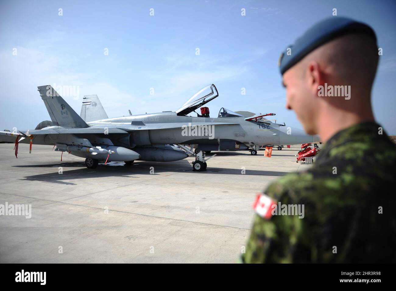 A Canadian soldier looks at a CF-18 as it sits loaded for flight at ...