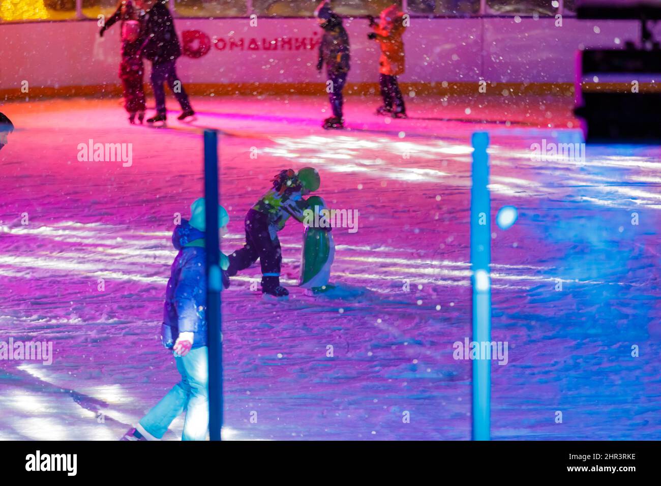 People skate in the evening on a lighted ice rink. A blizzard is raging ...