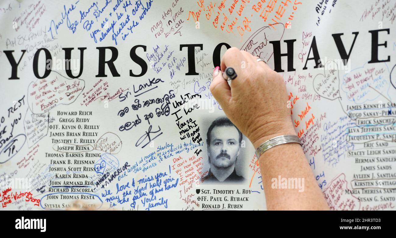 A family member of firefighter Sgt. Timothy Roy signs a poster on the ...