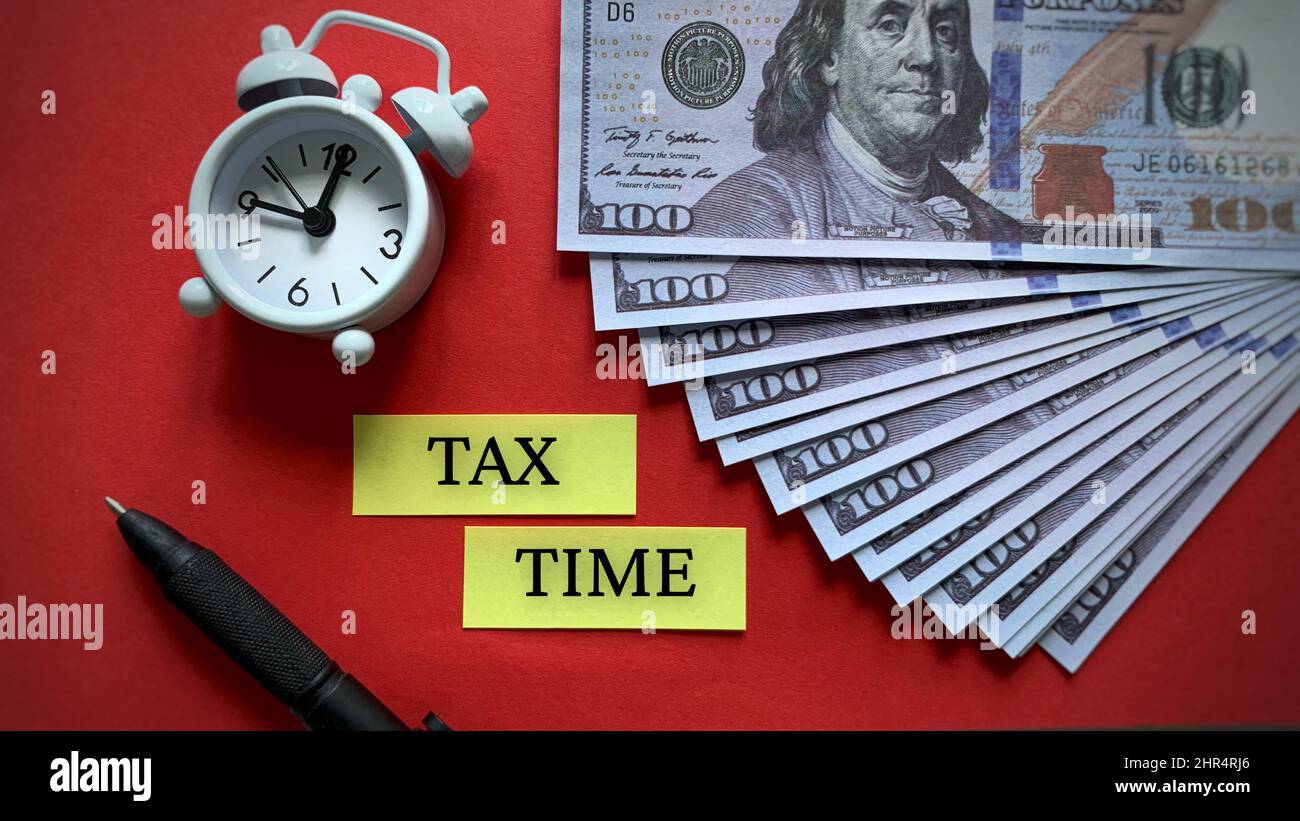 Top view of text - Tax time. With bank notes, pen and white clock ...