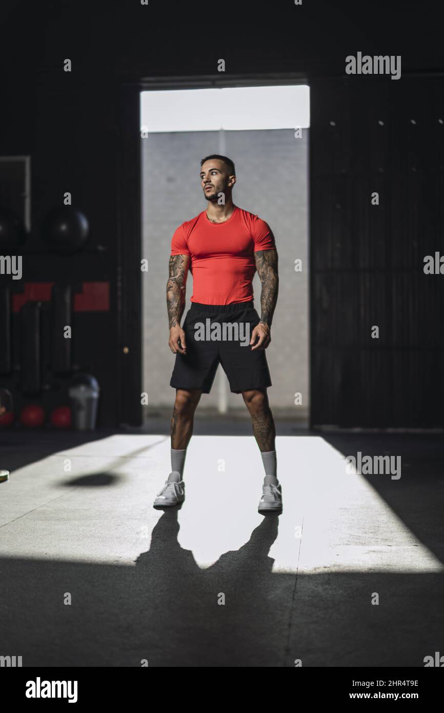 Vertical shot of an athlete posing in the gym wearing a red workout ...