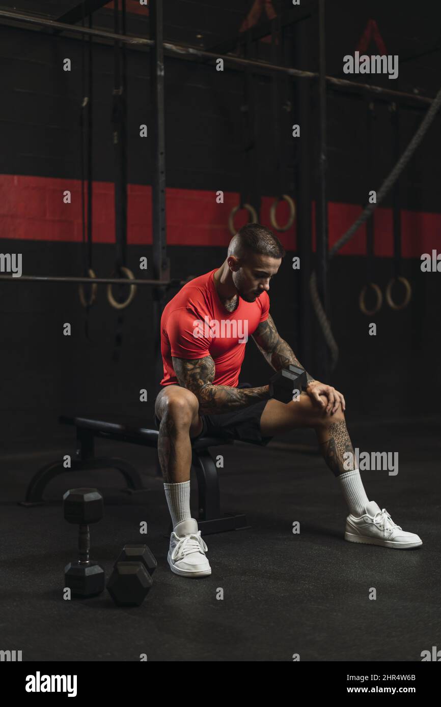Strong muscular European guy with cool tattoos working out in a gym ...
