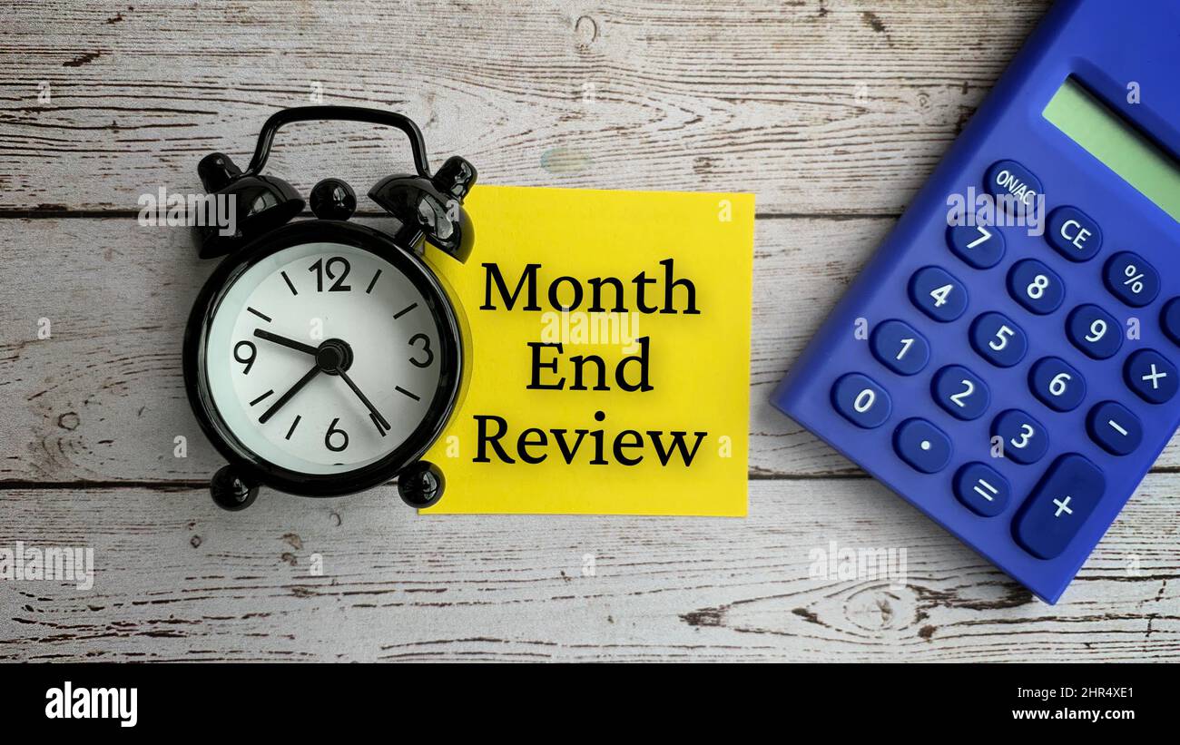 Top view of text on yellow notepad - Month end review with alarm clock ...