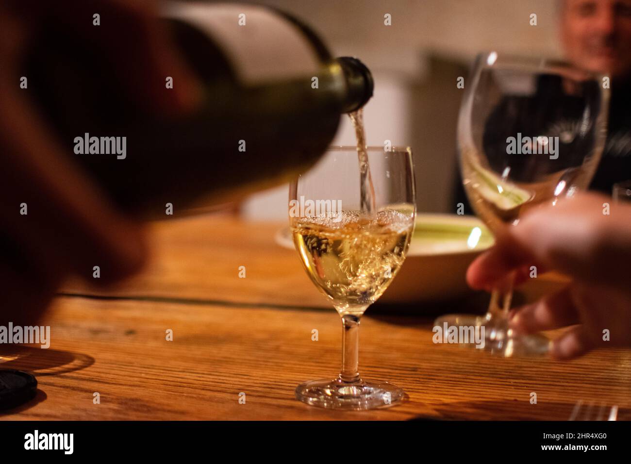 Hand pouring white wine into the glass Stock Photo - Alamy