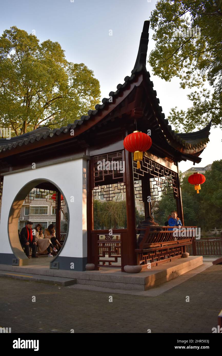 Vertical shot of a Chinese style alcove with people resting inside in ...