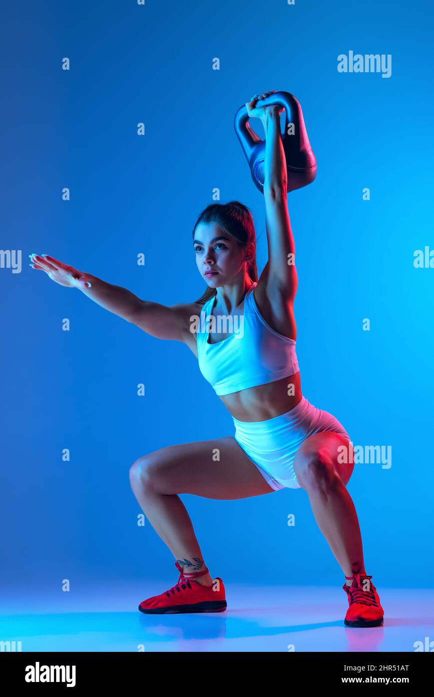 Dumbbell squats. Young sportive girl training with sports equipment ...