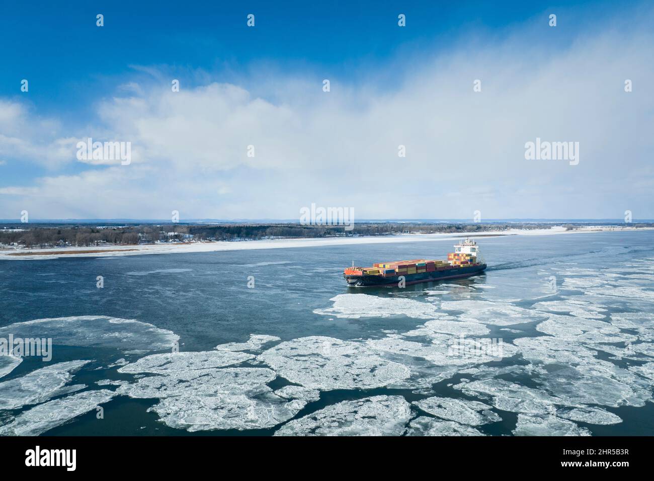 Aerial view of a container ship going upstream through winter ice in ...