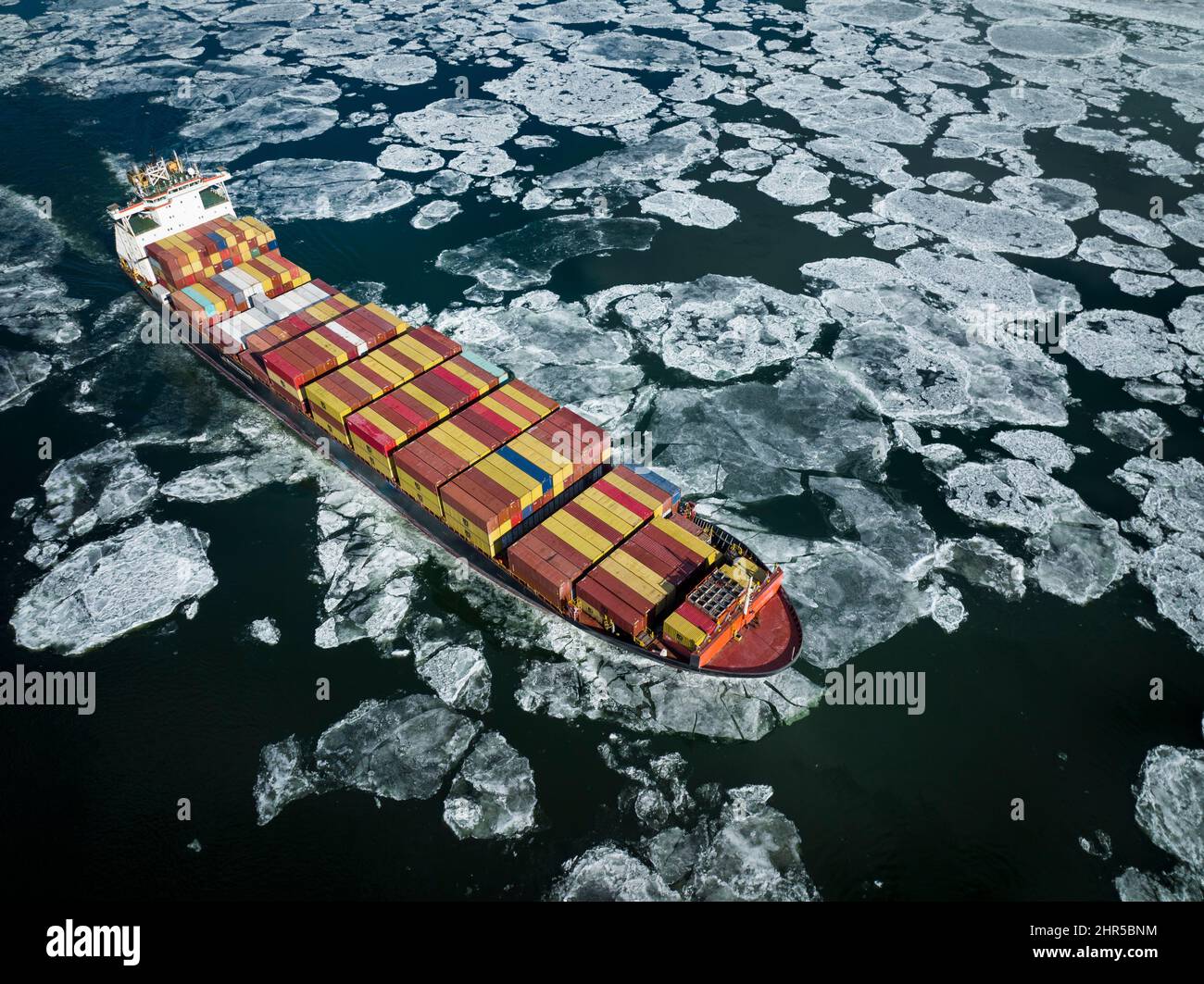 Aerial view of a container ship going upstream through winter ice in ...
