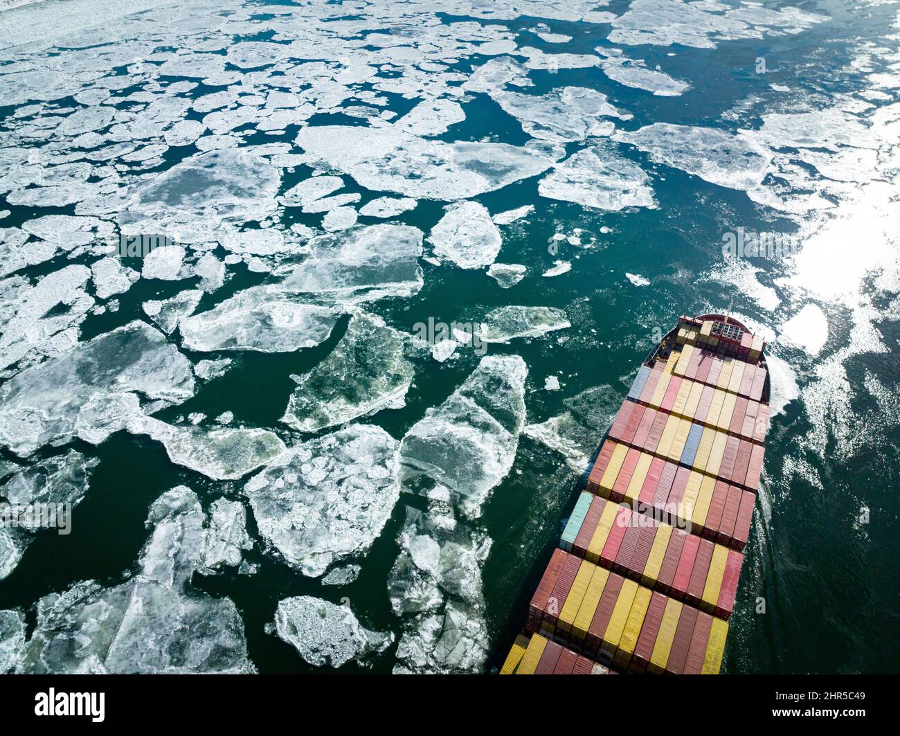 Aerial view of a container ship going upstream through winter ice in ...