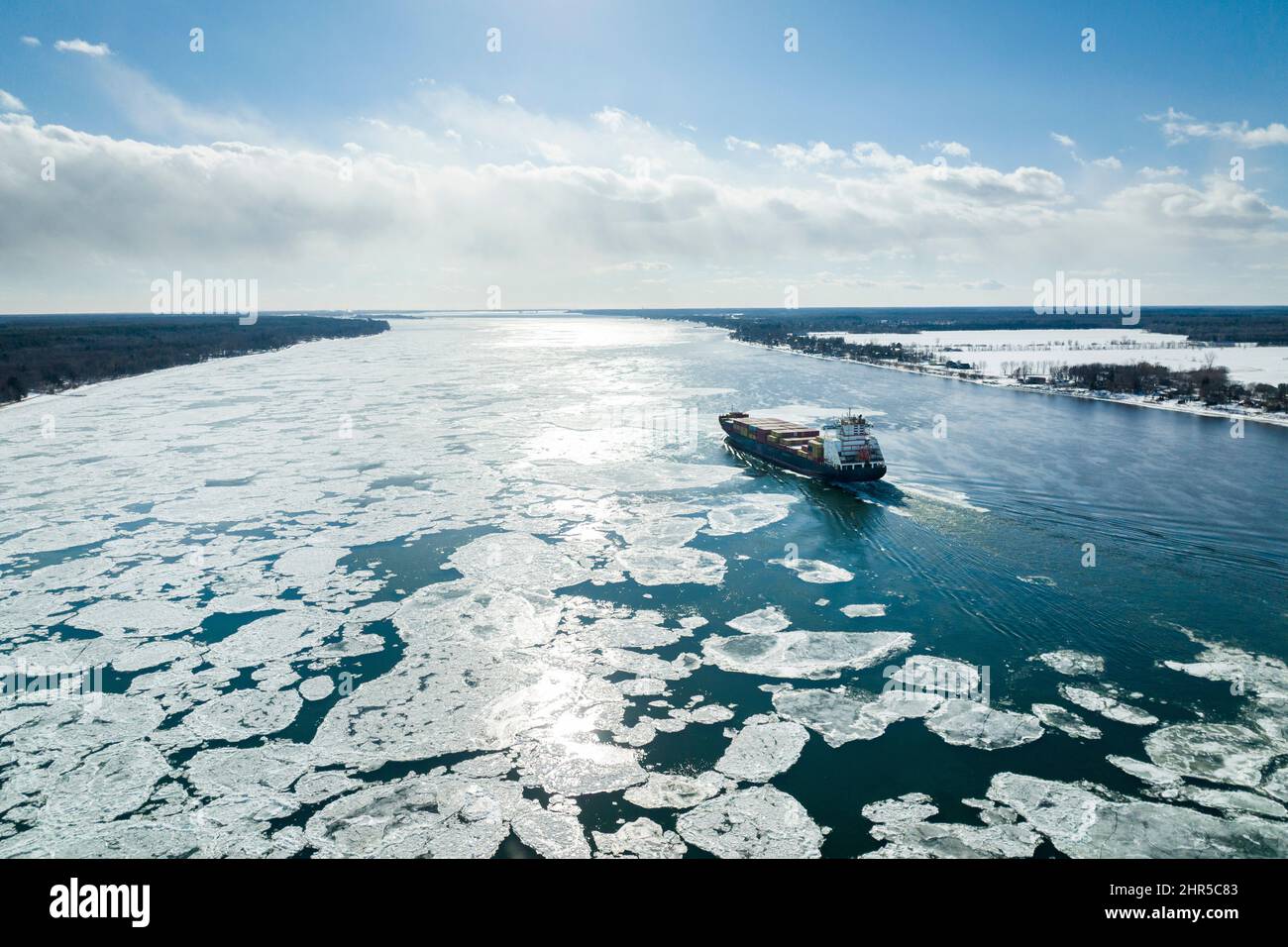 Aerial view of a container ship going upstream through winter ice in ...