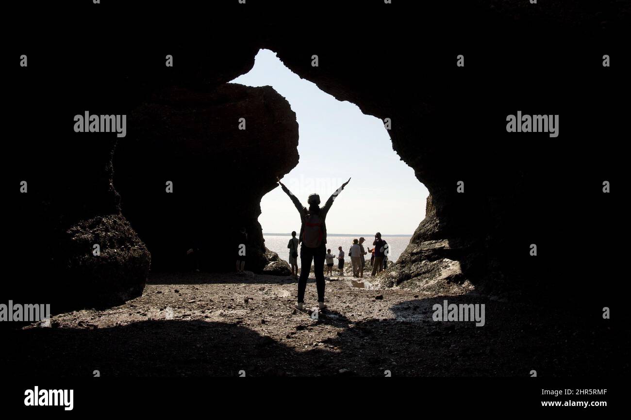 A tourist stops to pose for a photo in a cave going through one of the ...