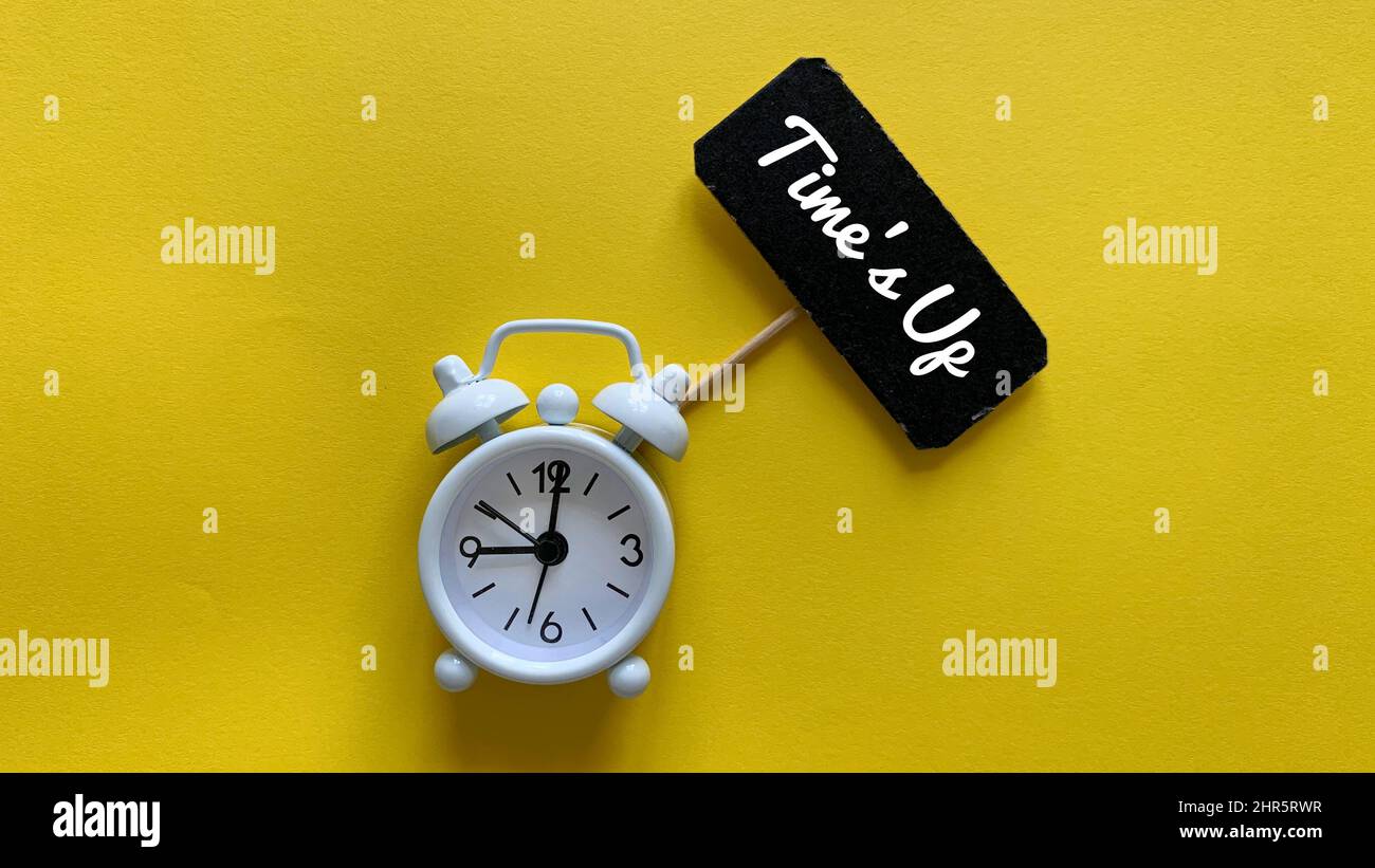 Alarm clock on yellow background with text on small black signage ...