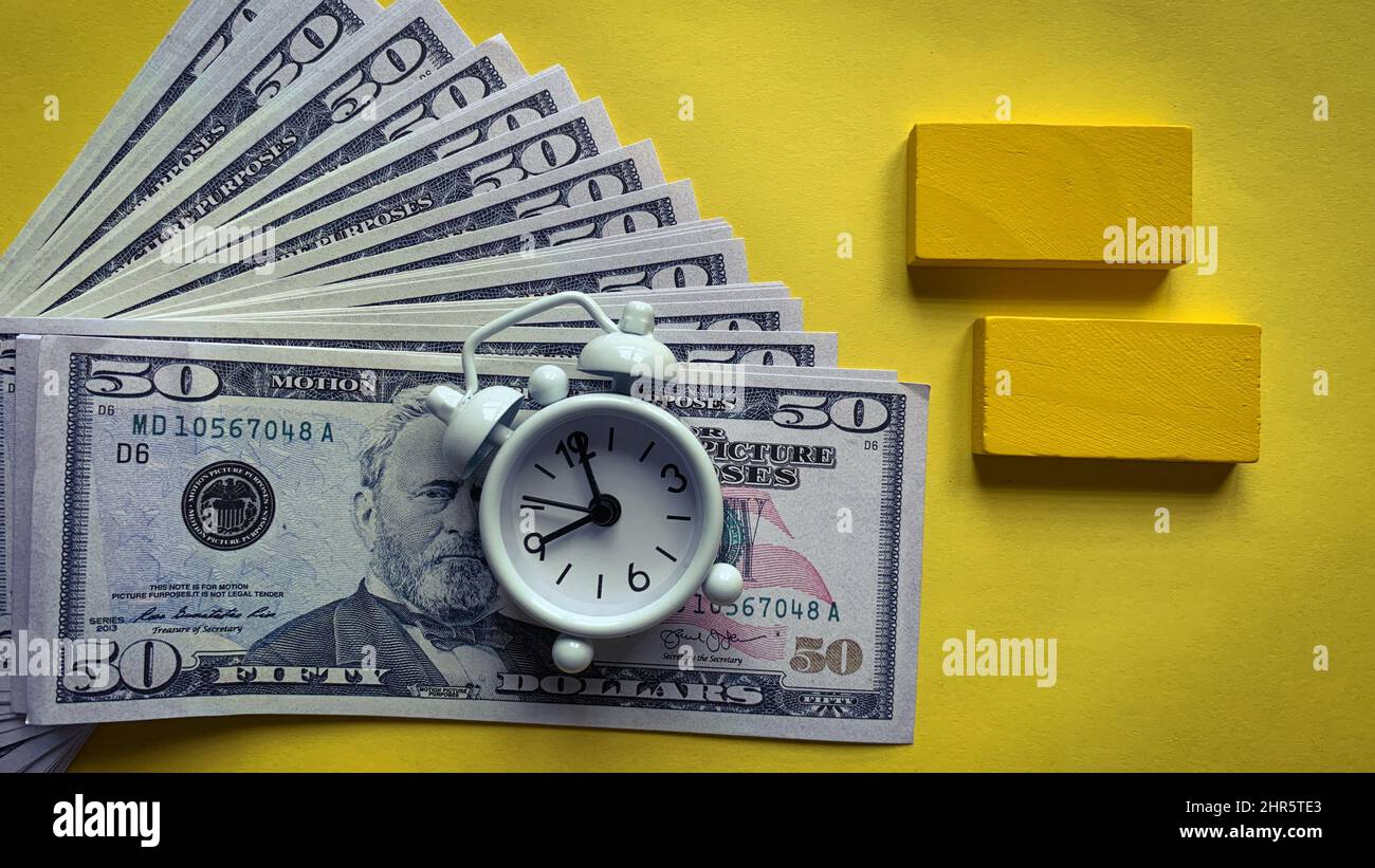 Top view of alarm clock with bank notes on yellow background. Copy ...