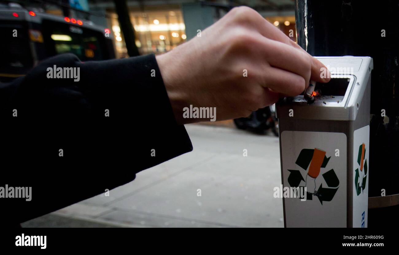 A smoker discards a cigarette butt into a recycling bin on Granville St ...