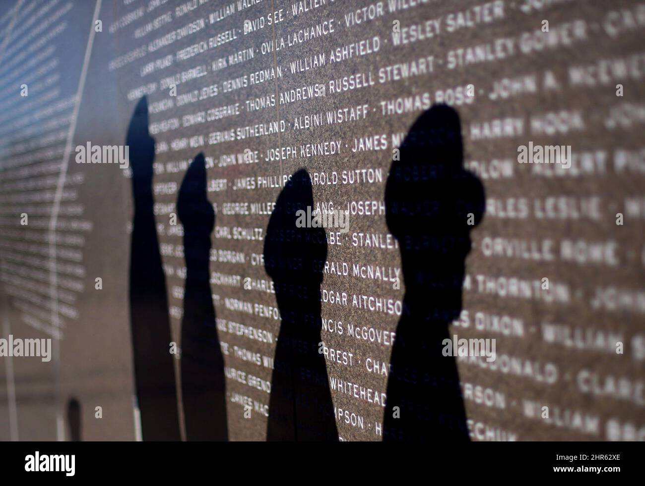 Firefighters pay their respects as their shadows are cast on the National Firefighters Memorial ...