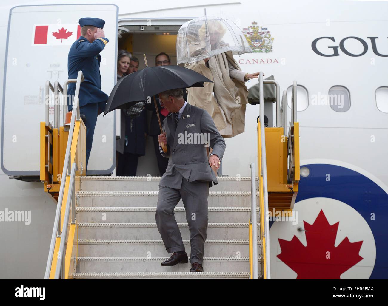 Prince Charles and his wife Camilla depart their plane on a rainy windy ...