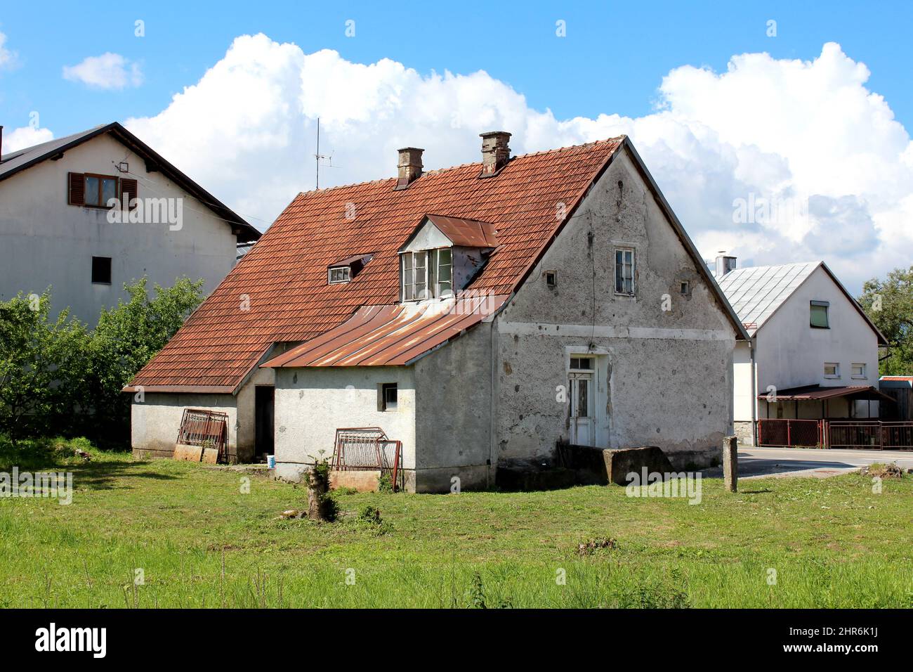 Abandoned small old suburban family house with dilapidated damaged white facade and red roof ...