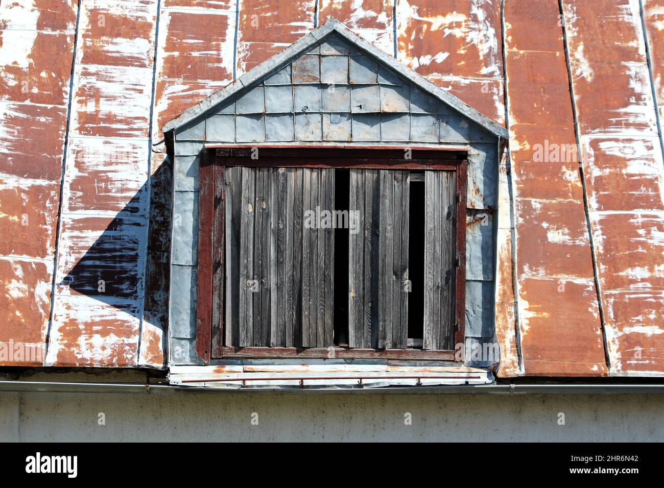 Boarded damaged old roof window with dilapidated dark brown cracked wooden window frame covered ...