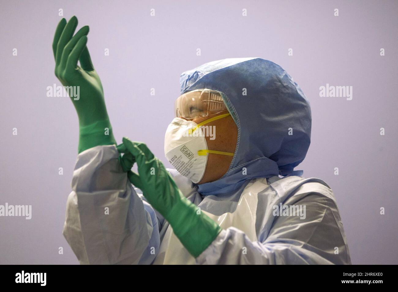 A healthcare professional pulls on a third pair of gloves during a ...