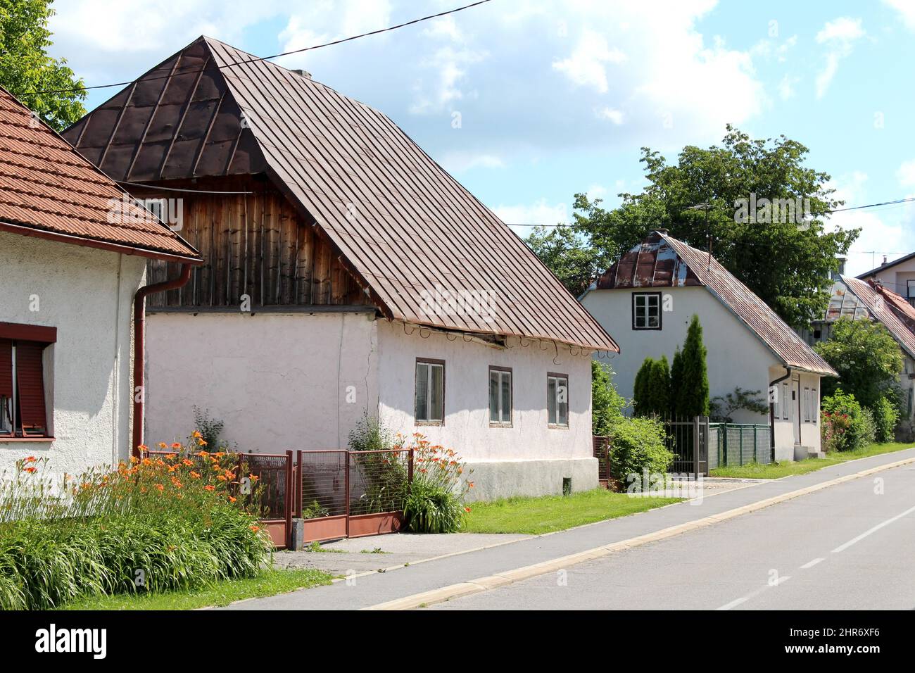 Row of small old rustic suburban family houses with dilapidated facade covered with rusted metal ...