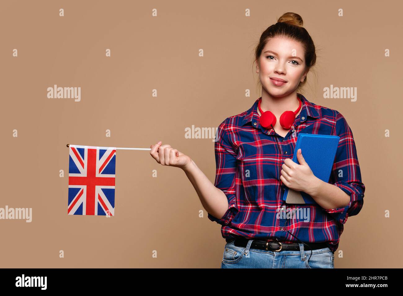 Smart Student girl holds small UK flag and notebook in studio on beige ...