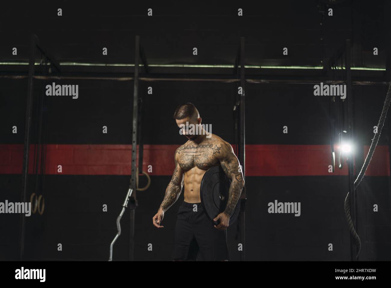 Strong muscular European guy with cool tattoos working out in a gym ...