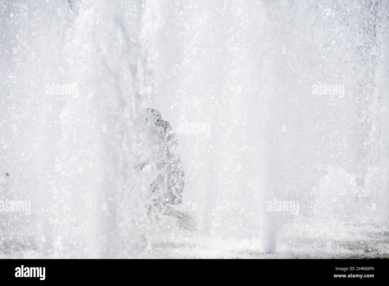 A young girl plays in a fountain to cool off at Queen Elizabeth Park in ...