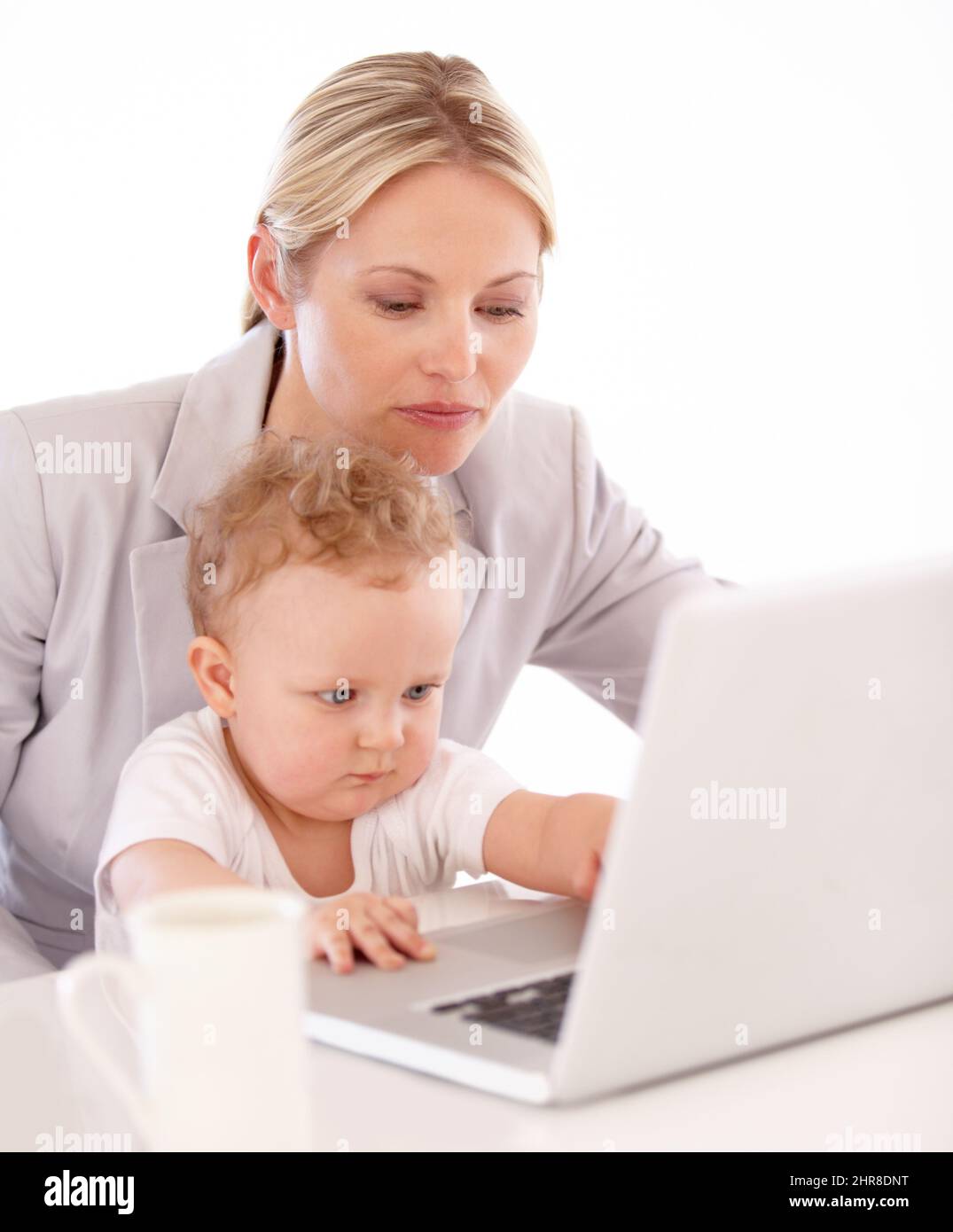 Working from home. A businesswoman working on her laptop with her baby ...