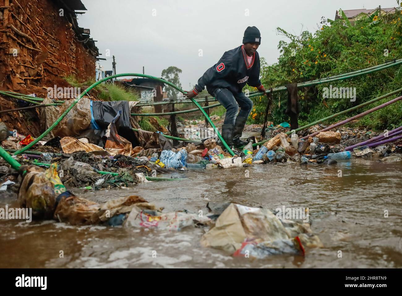 A boy saves his water pipes from a local river chocked with plastics ...