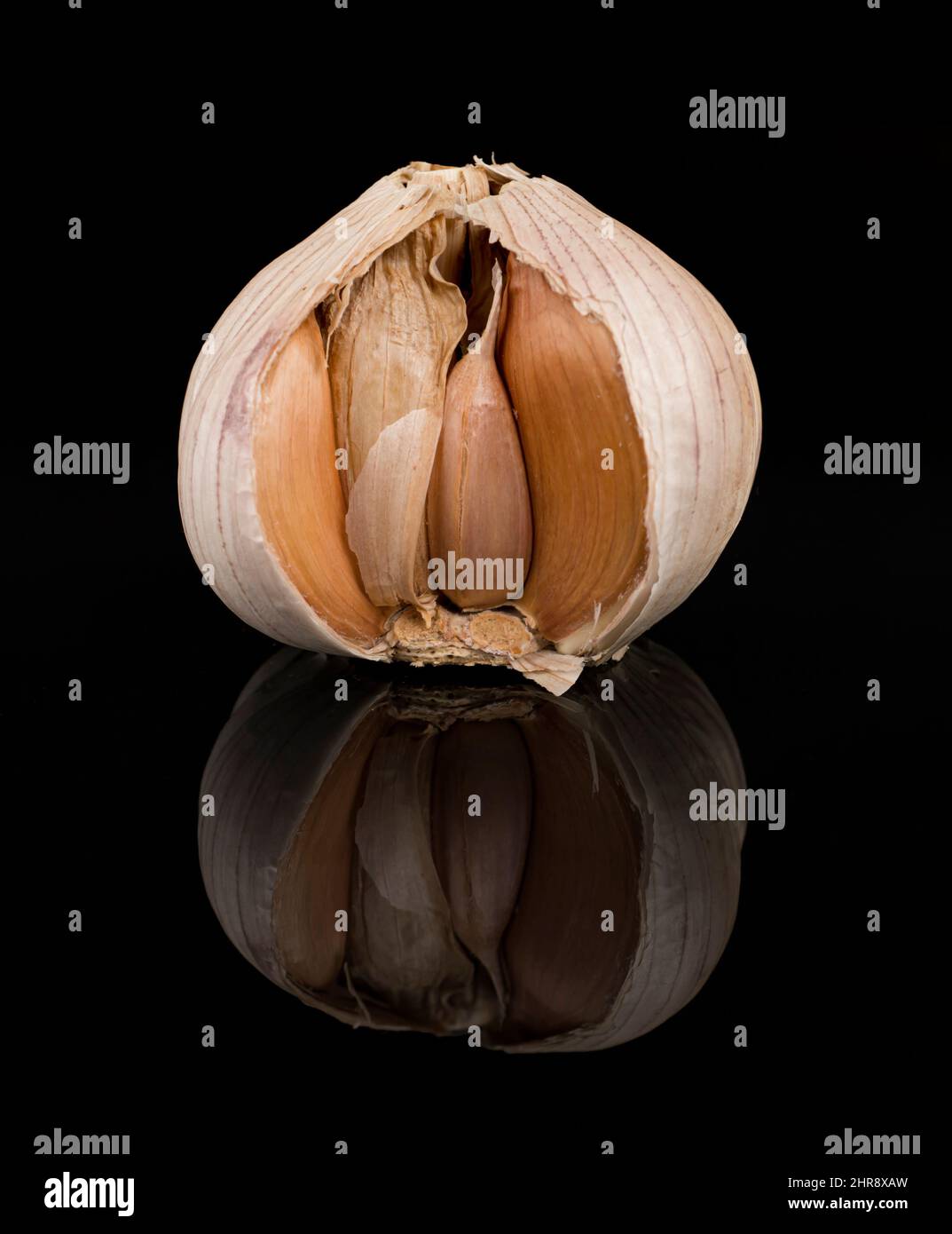 garlic in the husk, on a black background in isolation, with reflection ...