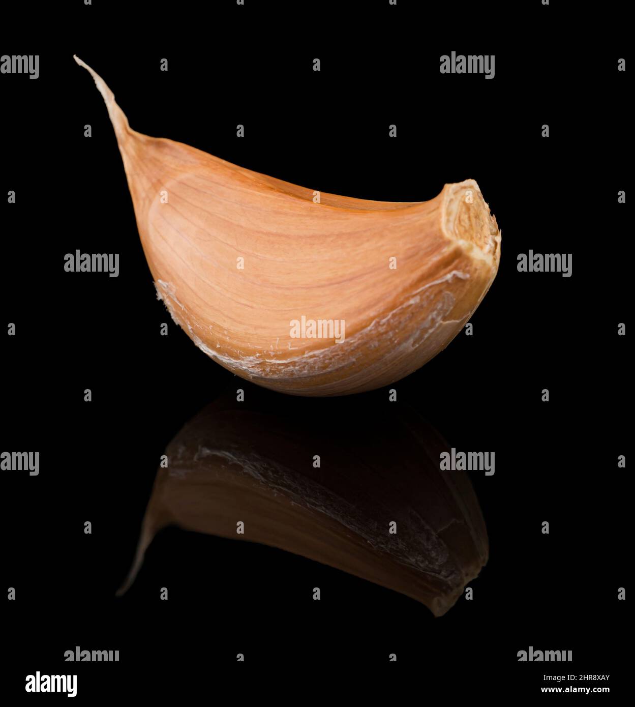 a clove of garlic in the husk, on a black background in isolation, with ...