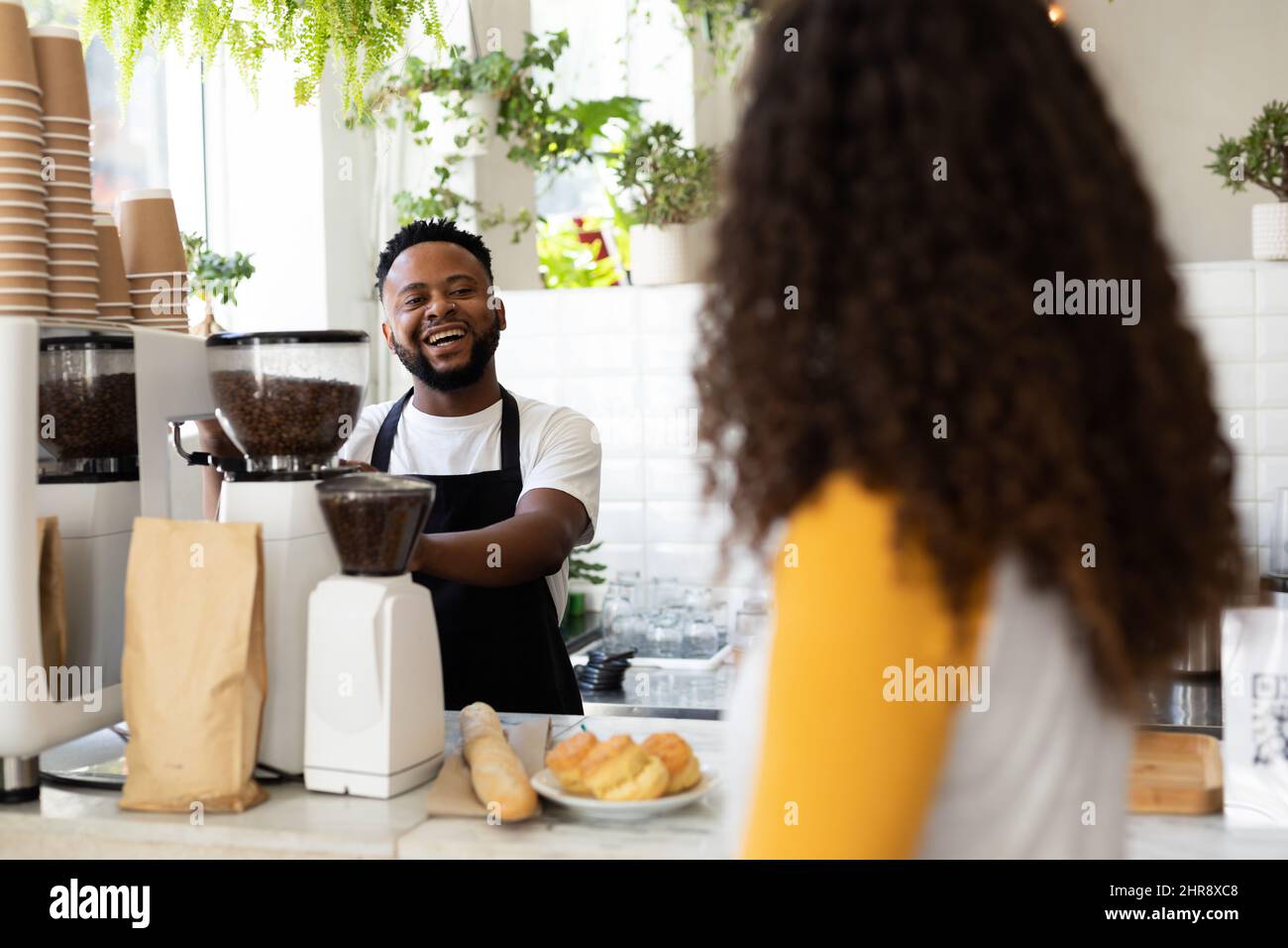 Happy african american barista talking with female customer at counter ...