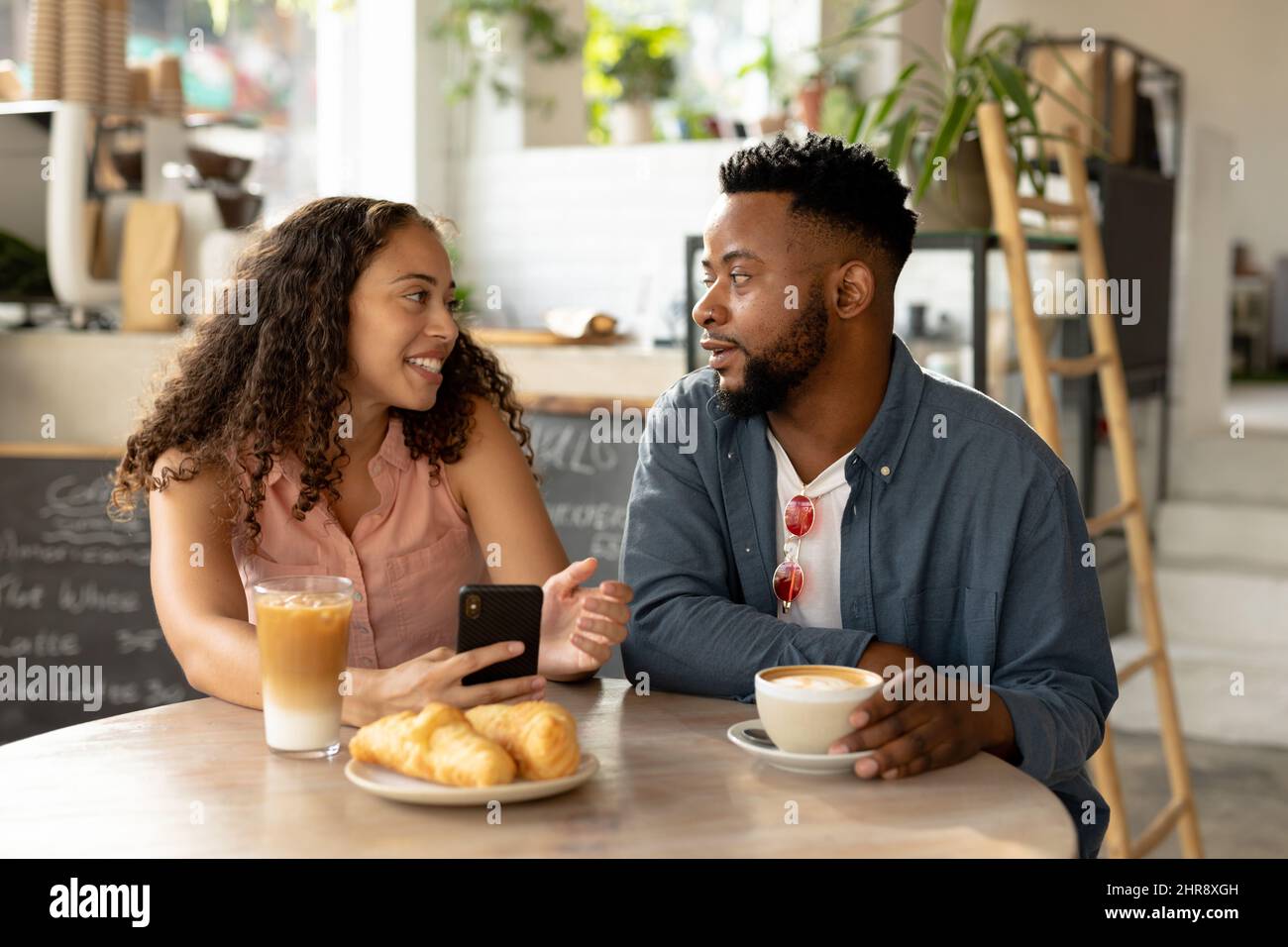 Happy african american couple talking while sitting with food and drink ...