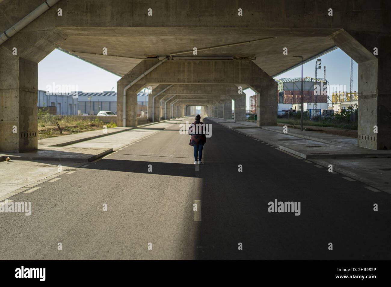 Back view of a female walking on a road under a stone bridge Stock ...